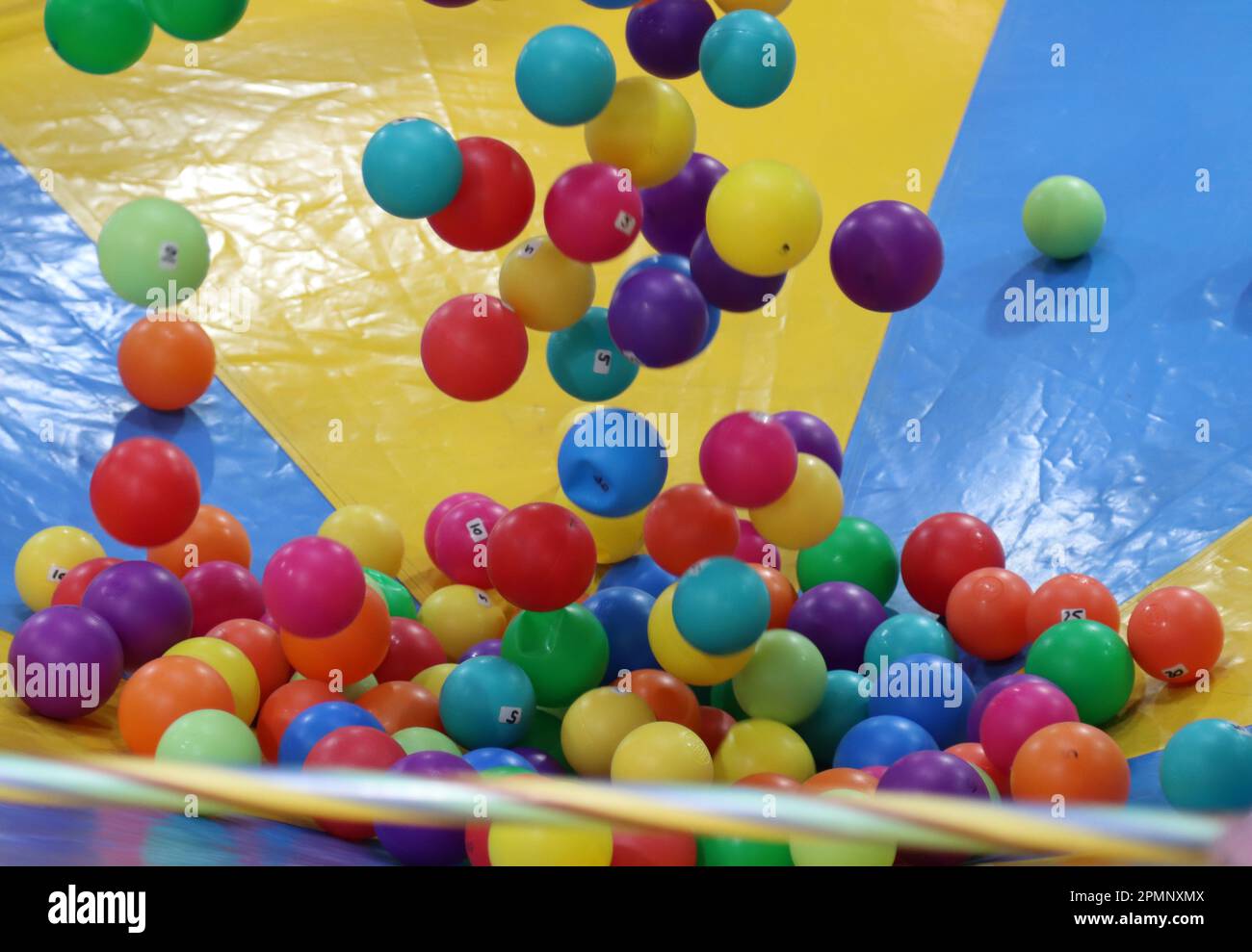 An array of colorful plastic balls is scattered and piled atop one ...