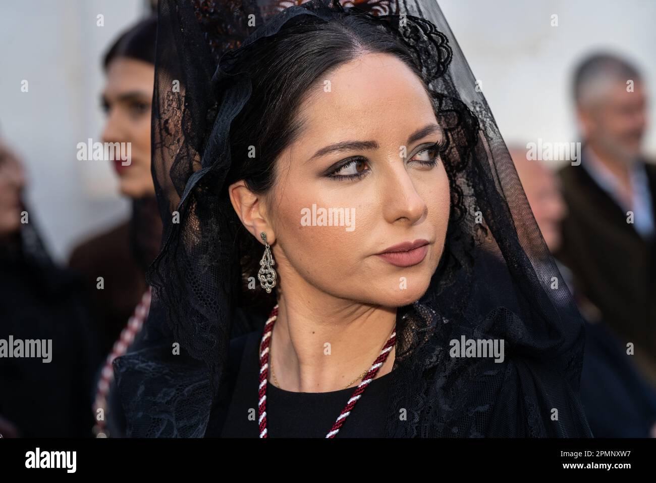 A Spanish woman wearing a black mantilla lace head covering prepares to ...
