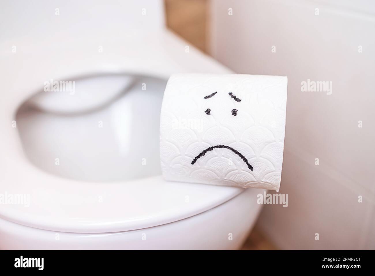 close-up, a roll of toilet paper with a painted sad face stands on the ...
