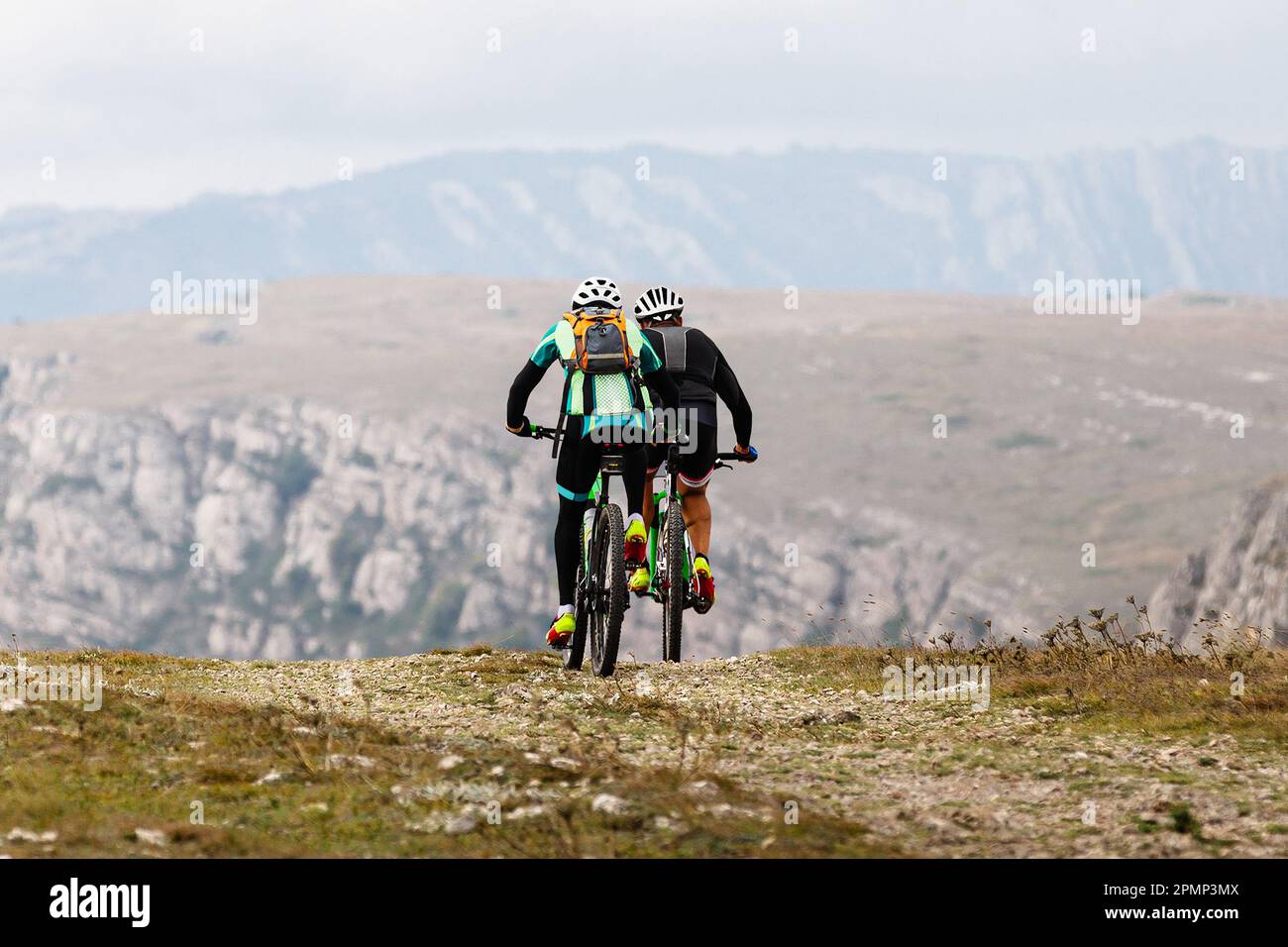 two male cyclist riding mountain cycle on mountainous region travelling ...