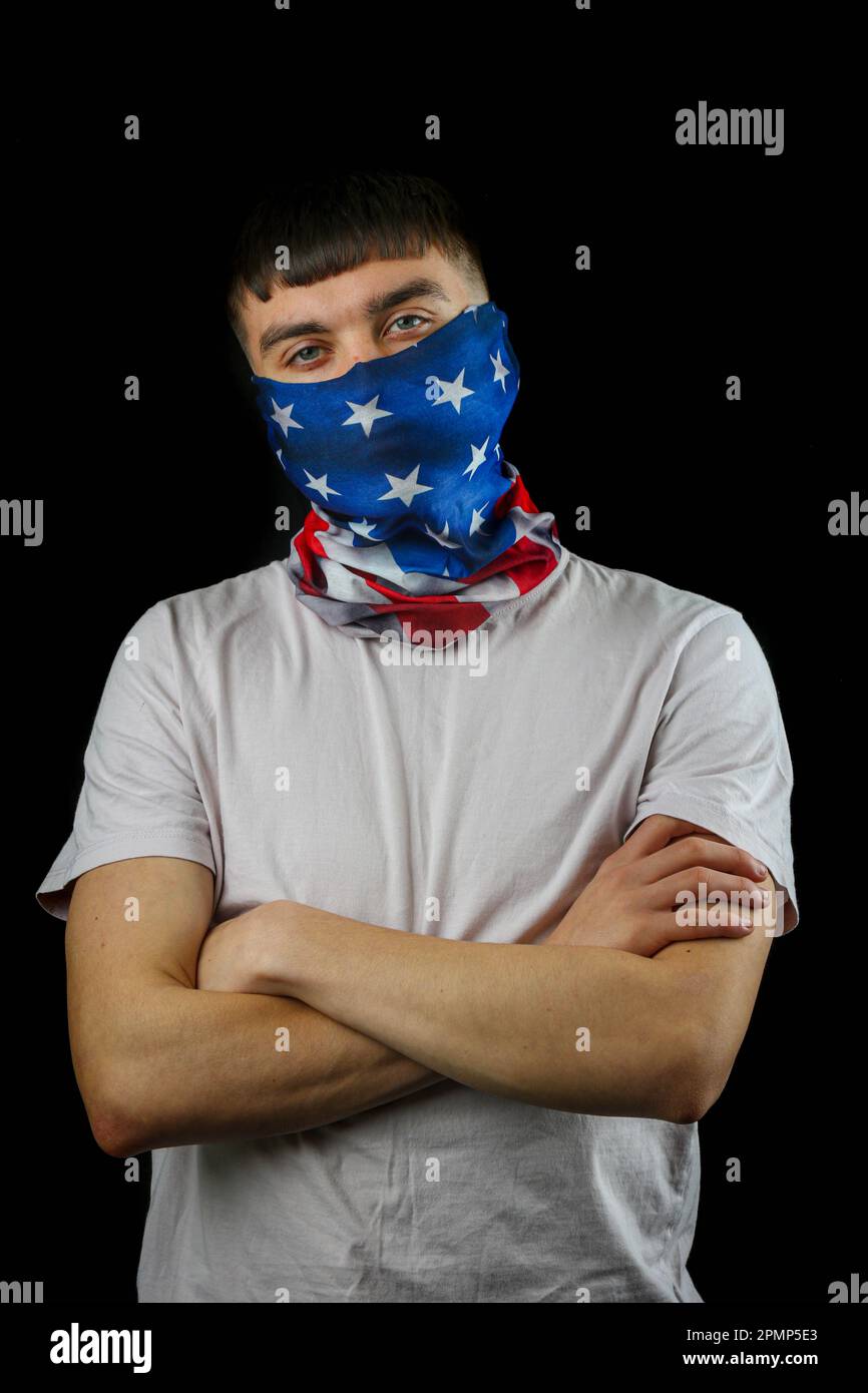 Teenage boy wearing an American flag mask against a black background ...
