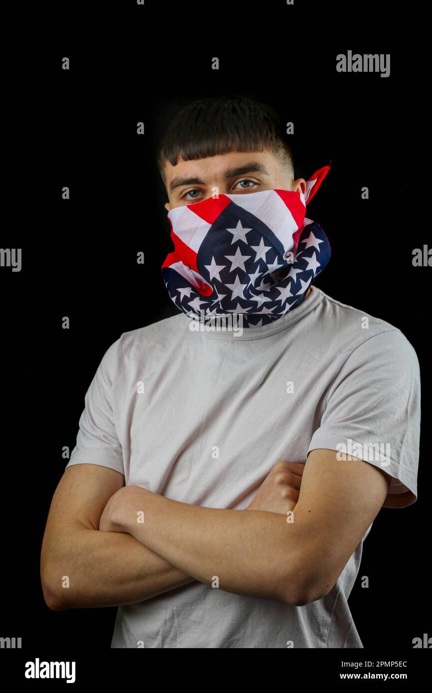Teenage boy wearing an American flag mask against a black background ...