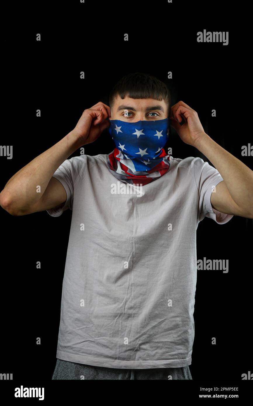 Teenage boy wearing an American flag mask against a black background ...