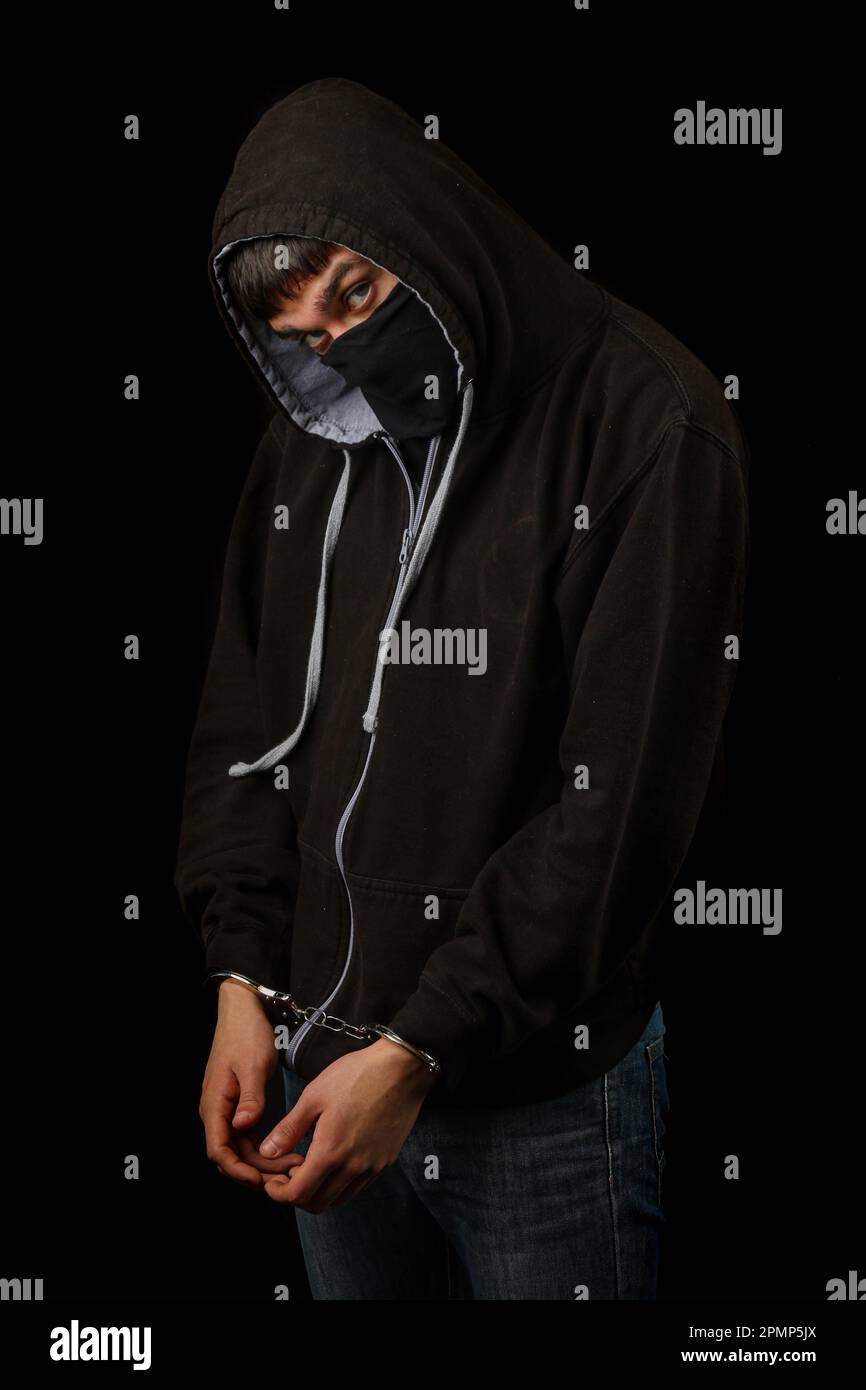 Arrested teenage boy in handcuffs wearing a mask and a hoodie Stock ...