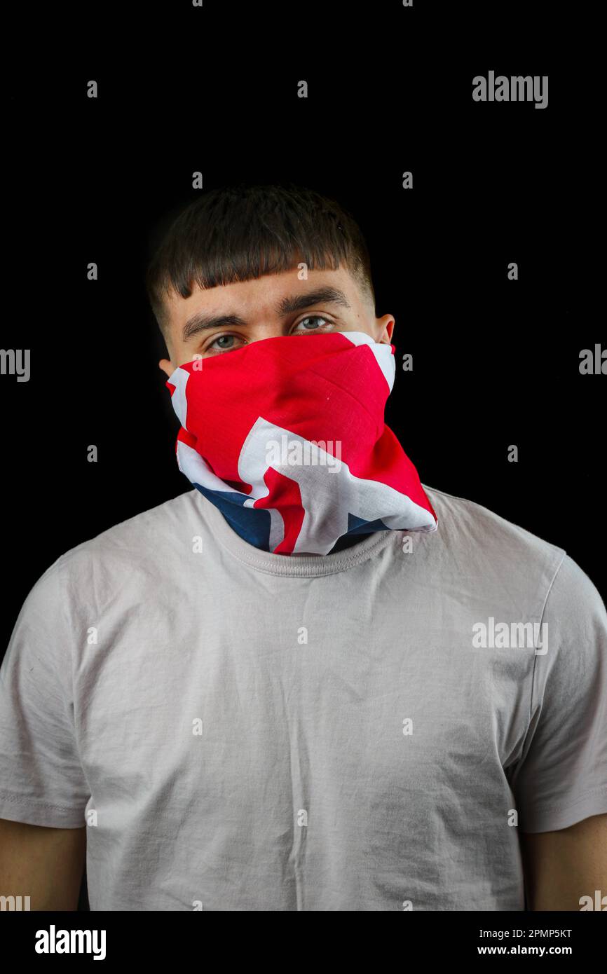 Teenage boy wearing an British flag mask against a black background ...