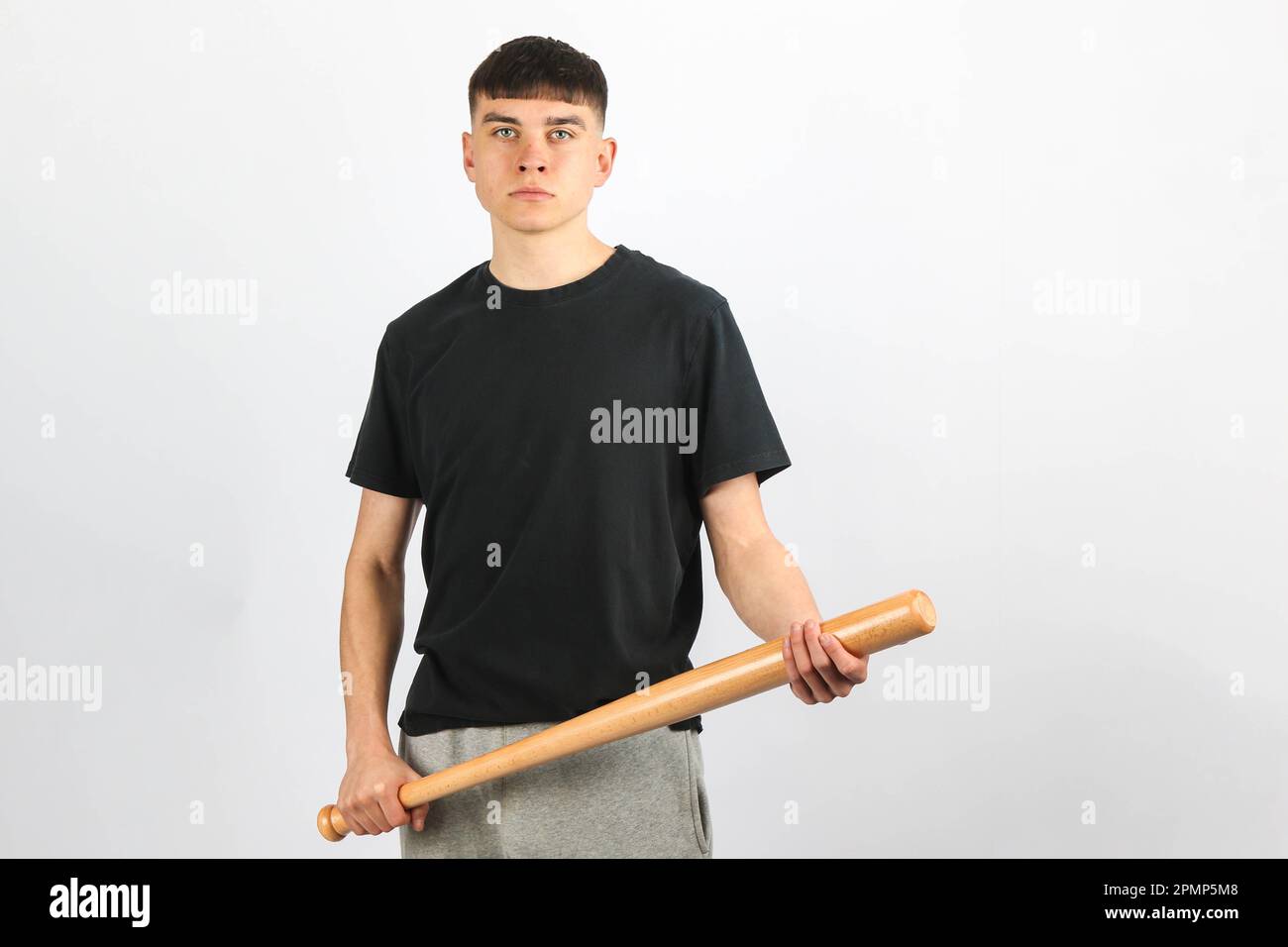 Teenage boy holding a baseball bat against a white background Stock ...