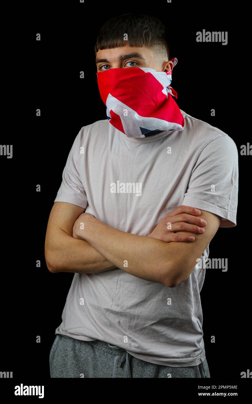 Teenage boy wearing an British flag mask against a black background ...