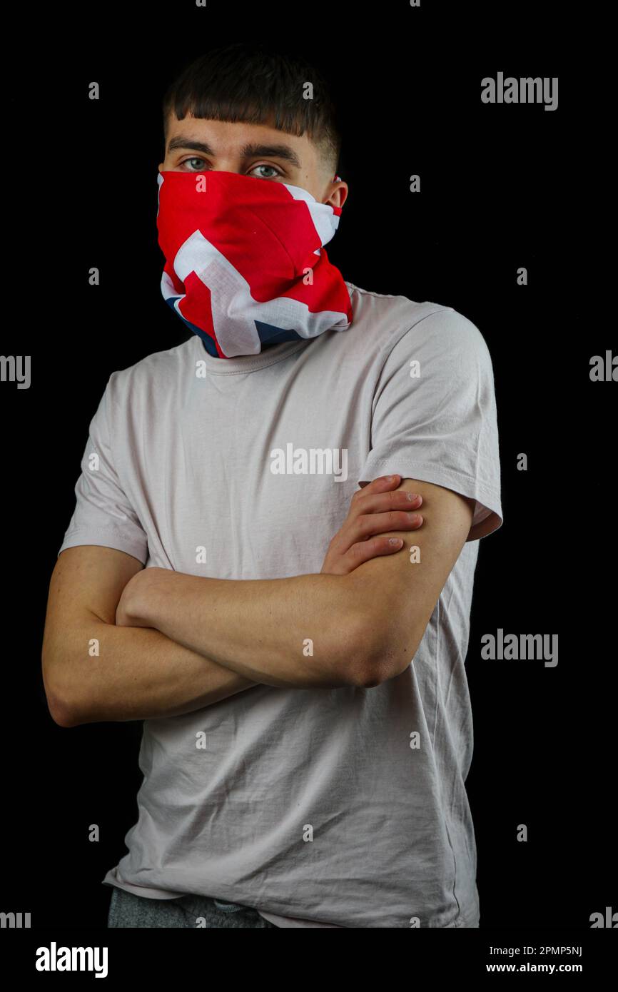 Teenage boy wearing an British flag mask against a black background ...