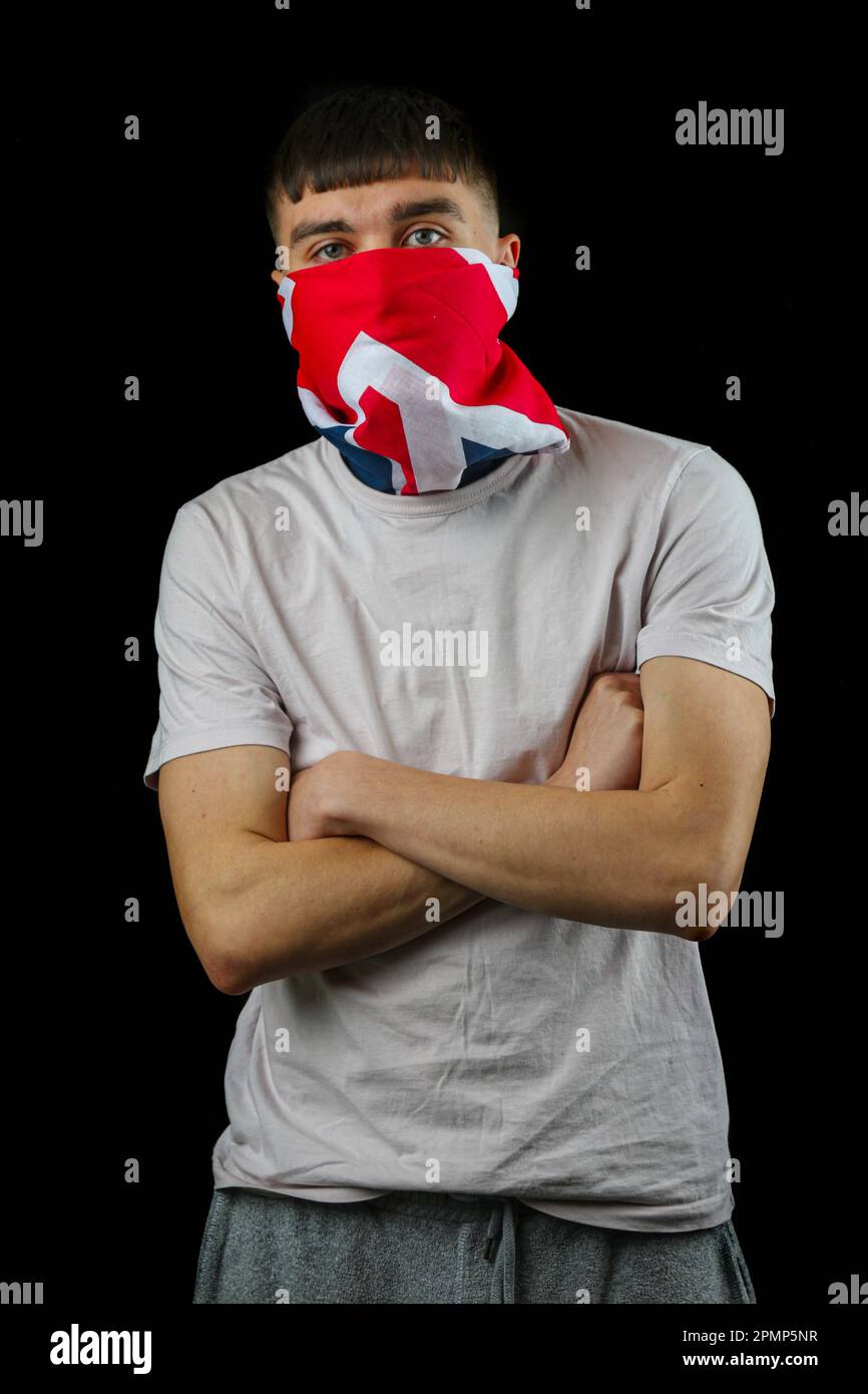 Teenage boy wearing an British flag mask against a black background ...