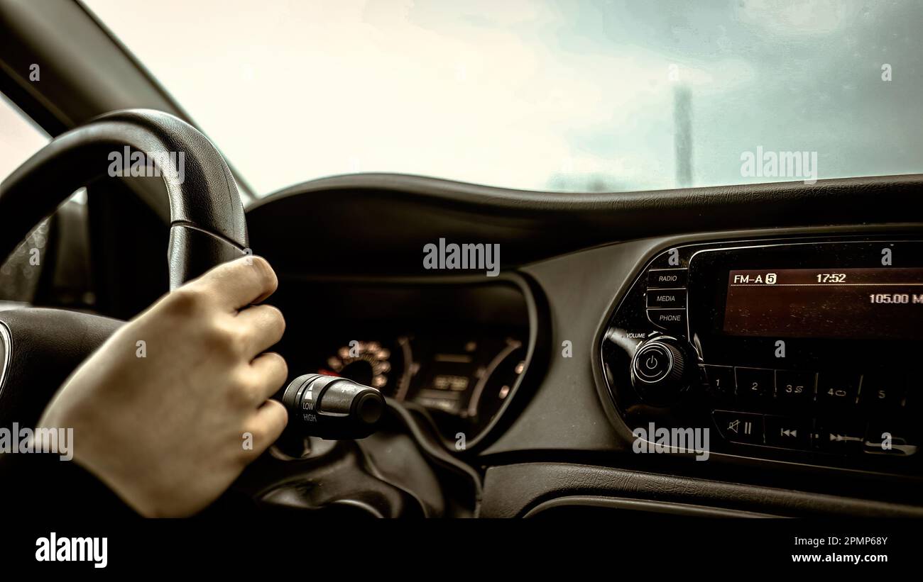 Close-up of hands gripping steering wheel while driving car on the road ...