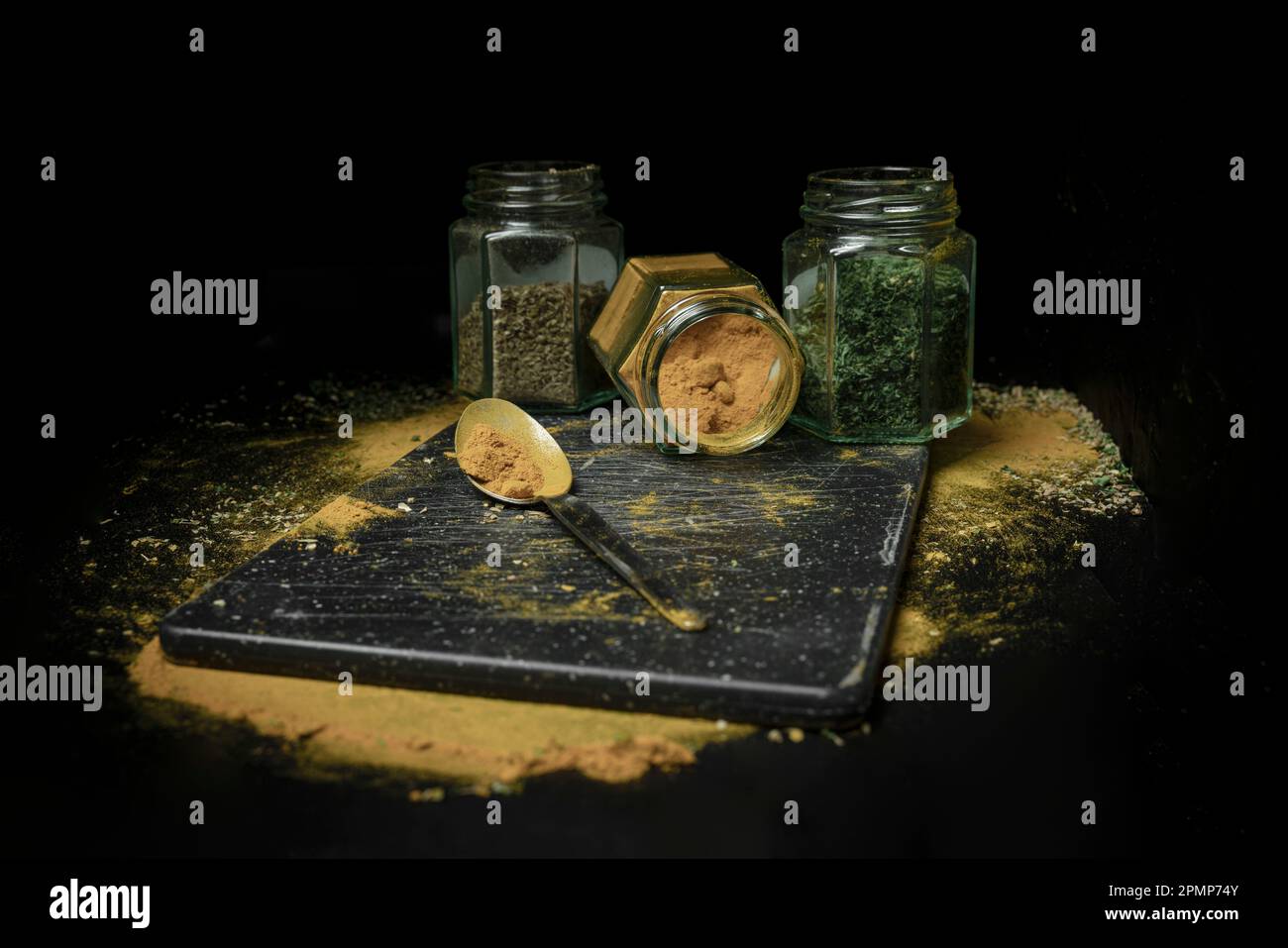 Three kinds of herbs or spices in glass jars sitting in a row on a ...