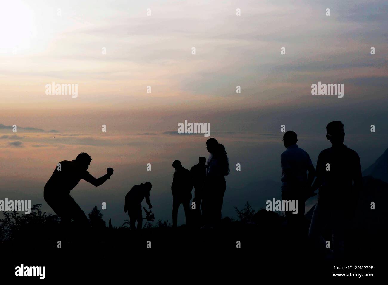 sun rises between the misty mountains and clouds and group of people ...