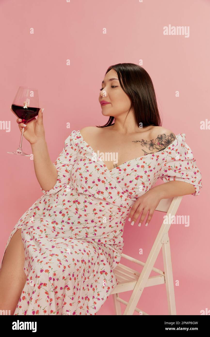 Portrait of young, beautiful, stylish girl in cute dress drinking wine ...