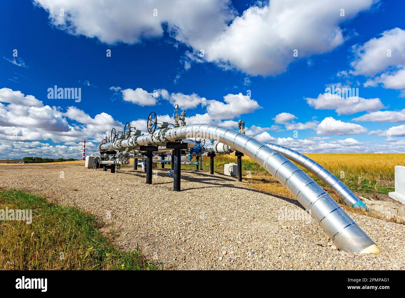 Oil pipeline with values, blue sky and clouds, West of Airdrie; Alberta ...