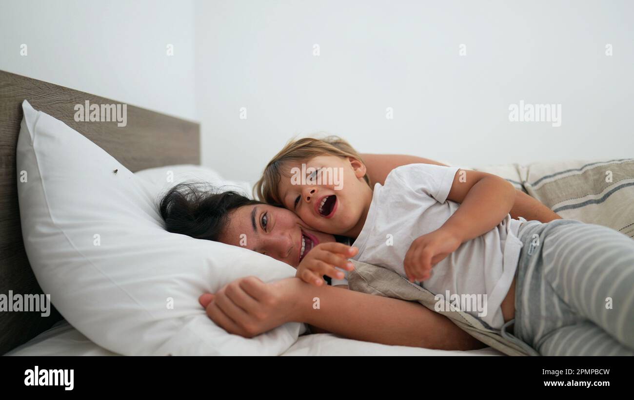 Mother and child laying in bed smiling. Happiness motherhood lifestyle ...