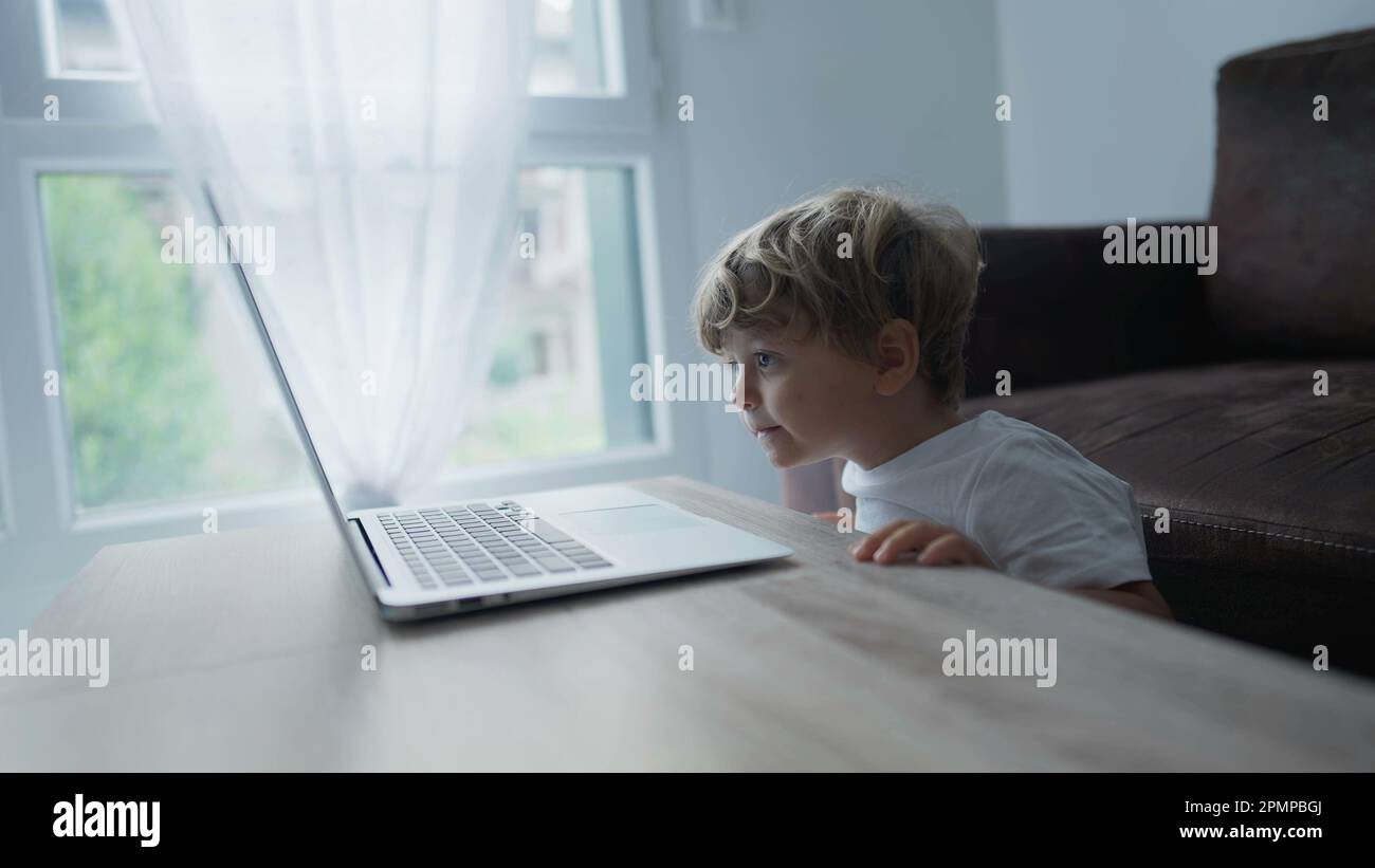 Child watching cartoons on laptop computer at home while eating apple ...