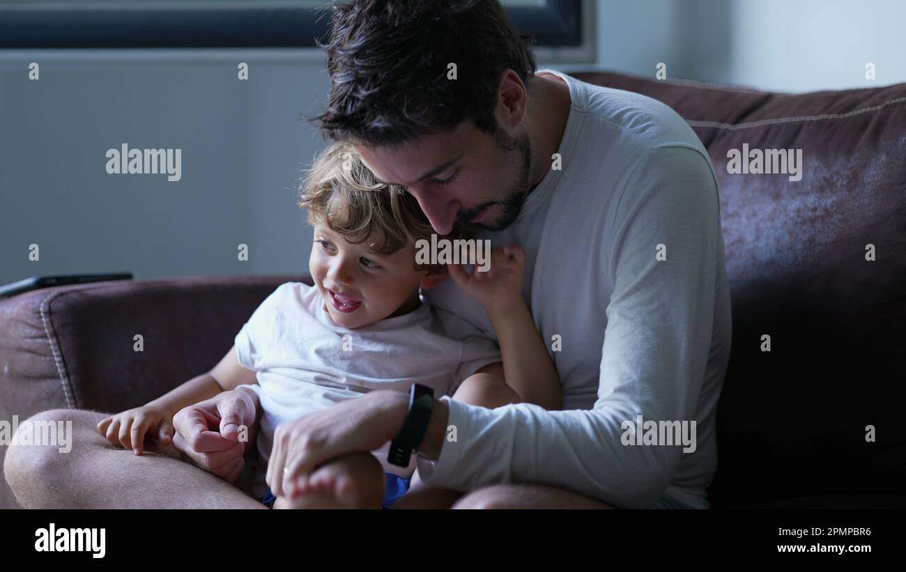Candid father and son relationship at home. Dad holding kid in lap ...