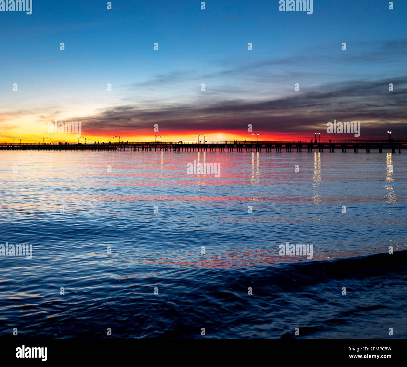 Vibrant sunset colours in the sky over the silhouetted White Rock pier ...