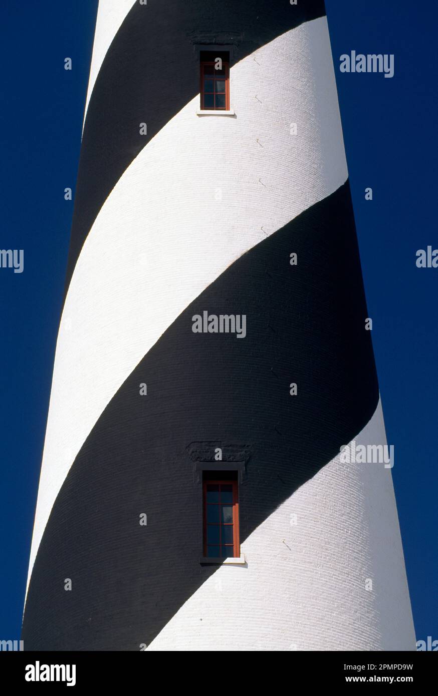 Close-view of a striped lighthouse in black and white against a blue ...