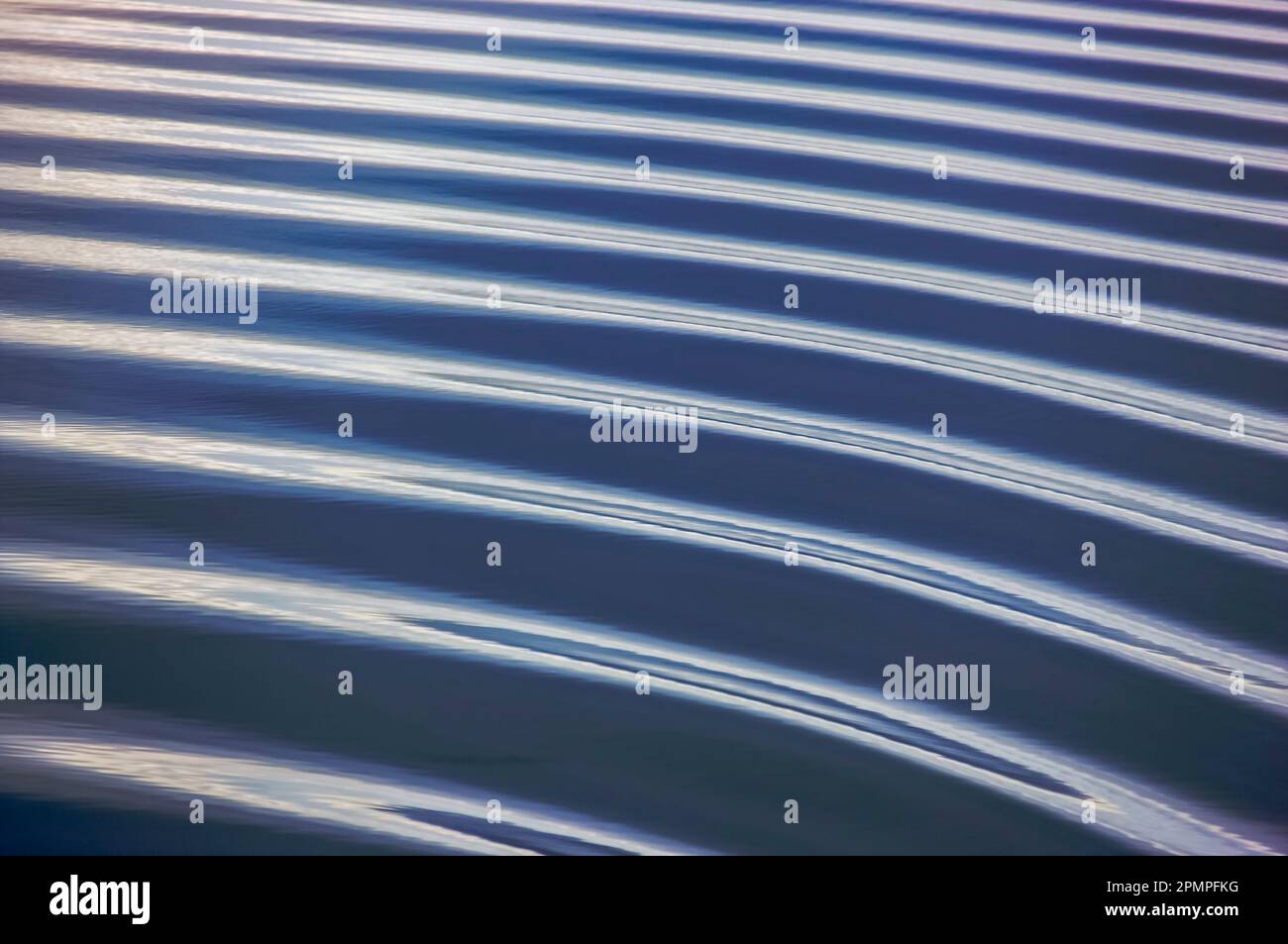 Ripples on the surface of the water reflecting sky and sunlight ...
