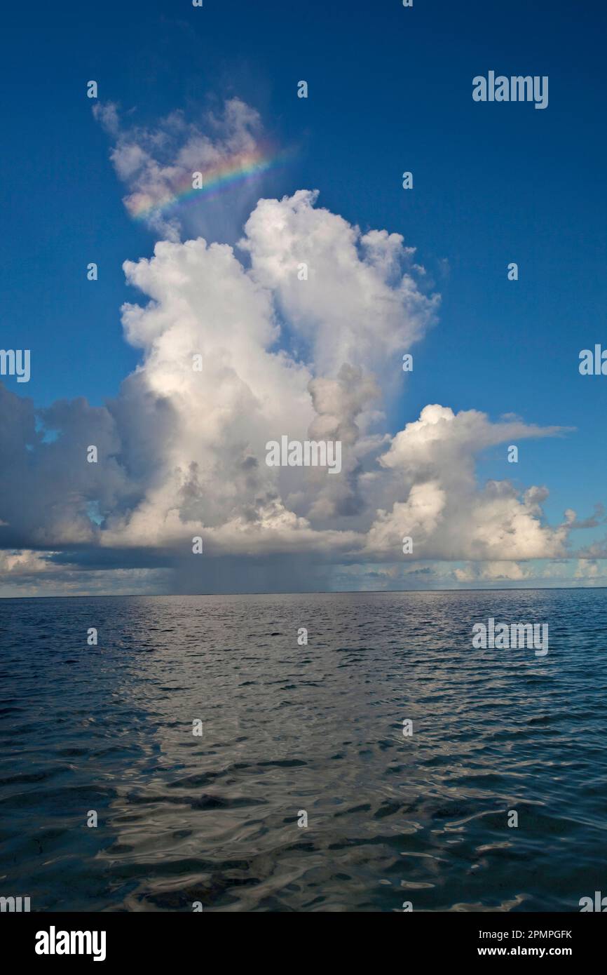 Small rainbow shines over storm clouds above the ocean; Seychelles ...
