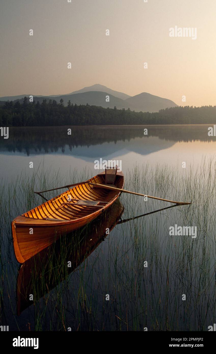 Boat with oars floating on a tranquil lake a twilight in Adirondack ...
