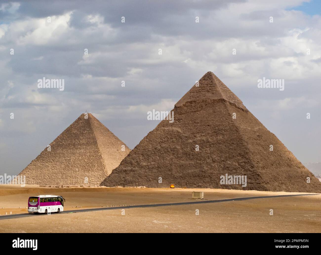 Tourist bus approaching two of the Great Pyramids of Giza; Giza, Egypt ...