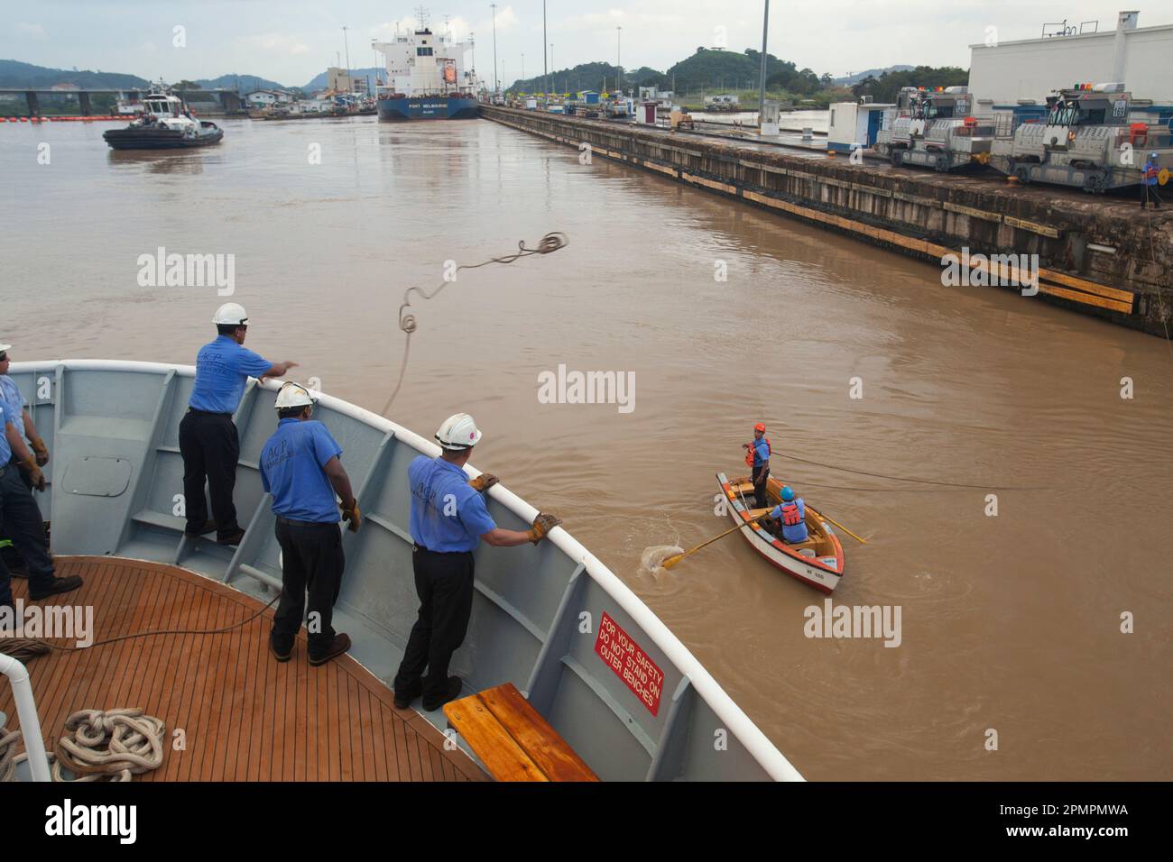 Workers toss rope to attach to guiding trains on the sides of a canal ...
