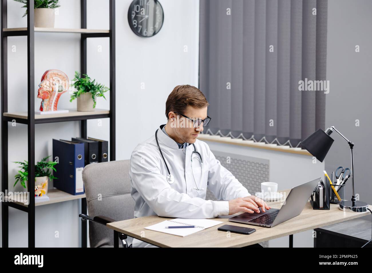 Doctor man sitting at the desk at his working place and working on ...