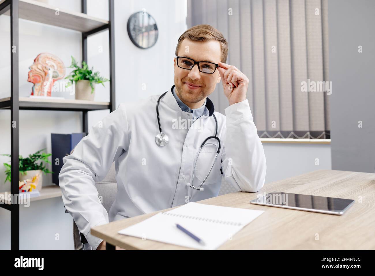 Portrait of young doctor wearing glasses and white uniform with ...