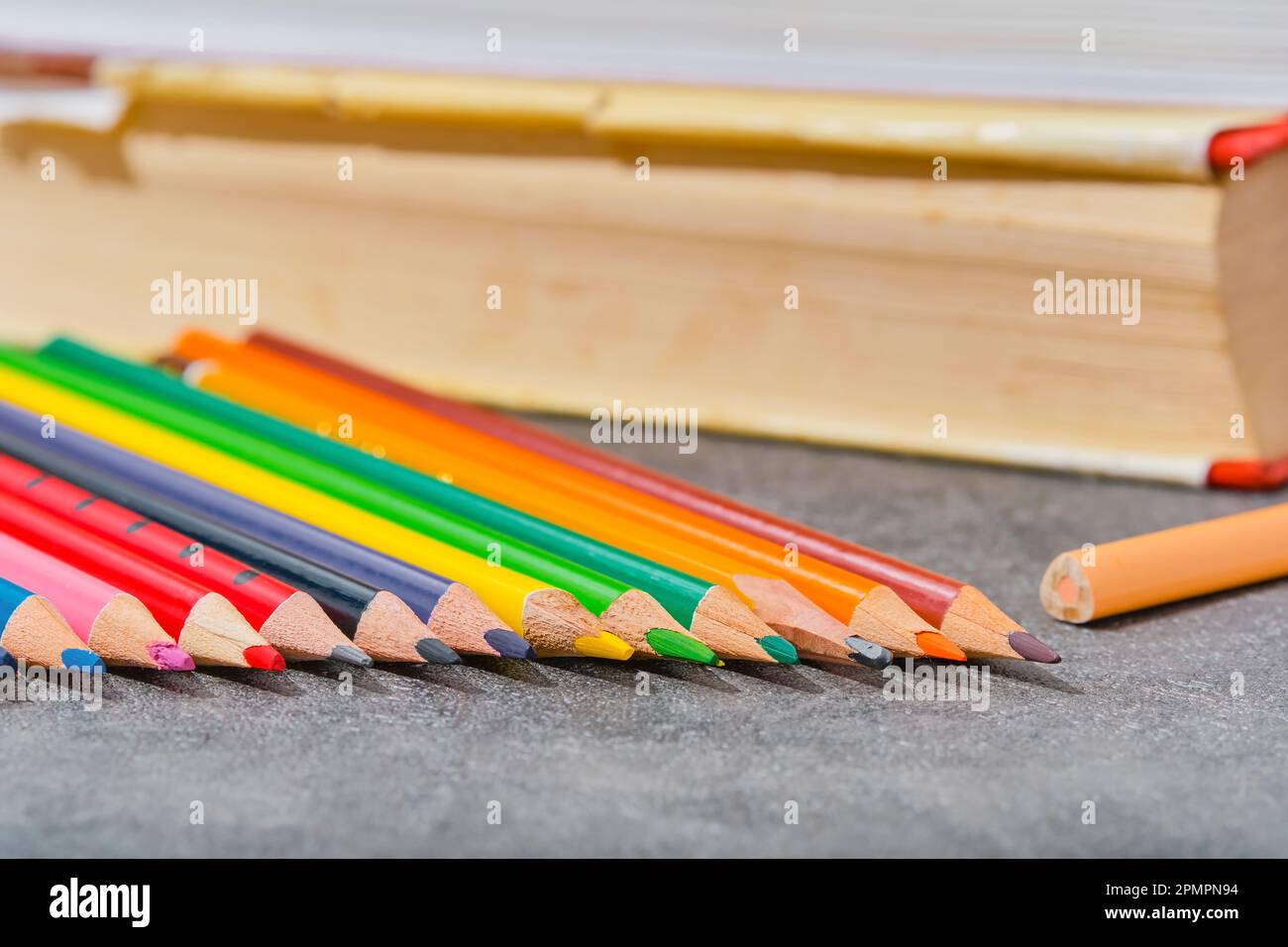 Colored pencils and old books on a light gray table, close-up ...