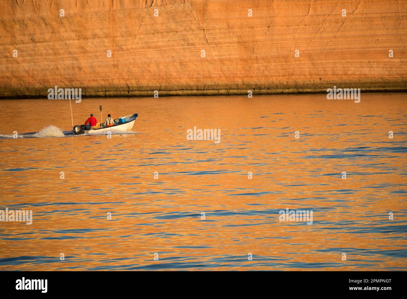 Boat passes by the sandstone cliffs of San Jose Island at sunrise; Baja ...