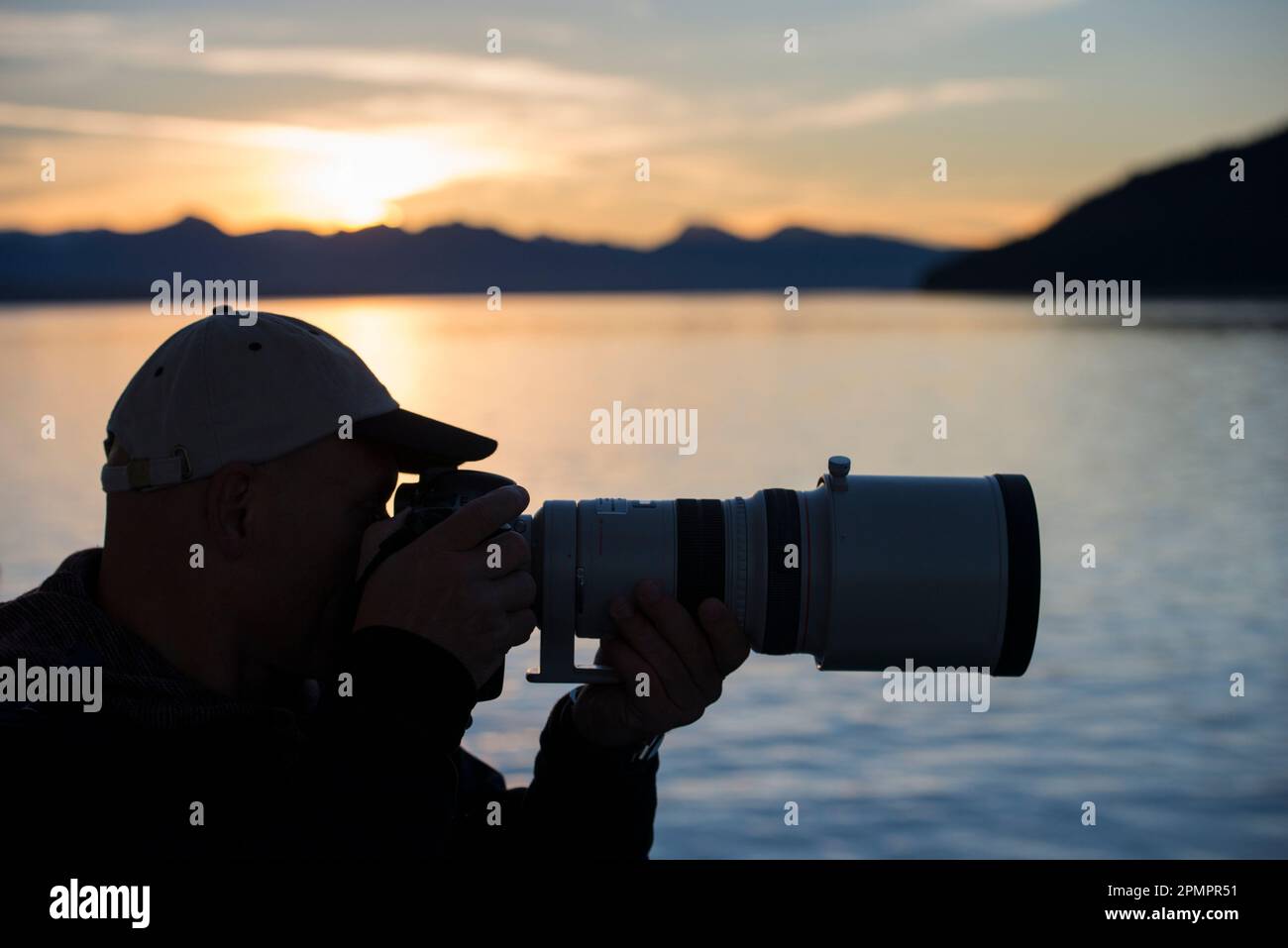 Silhouette of a photographer shooting a photo using a long lens; Inside ...