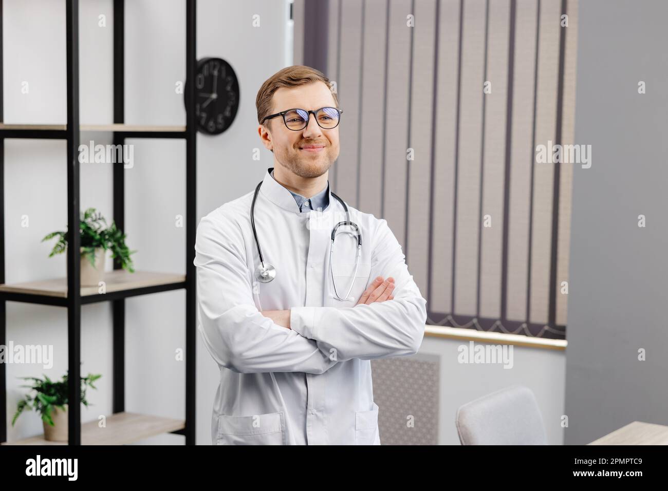 Smiling doctor posing with arms crossed in the office. Man is wearing a ...