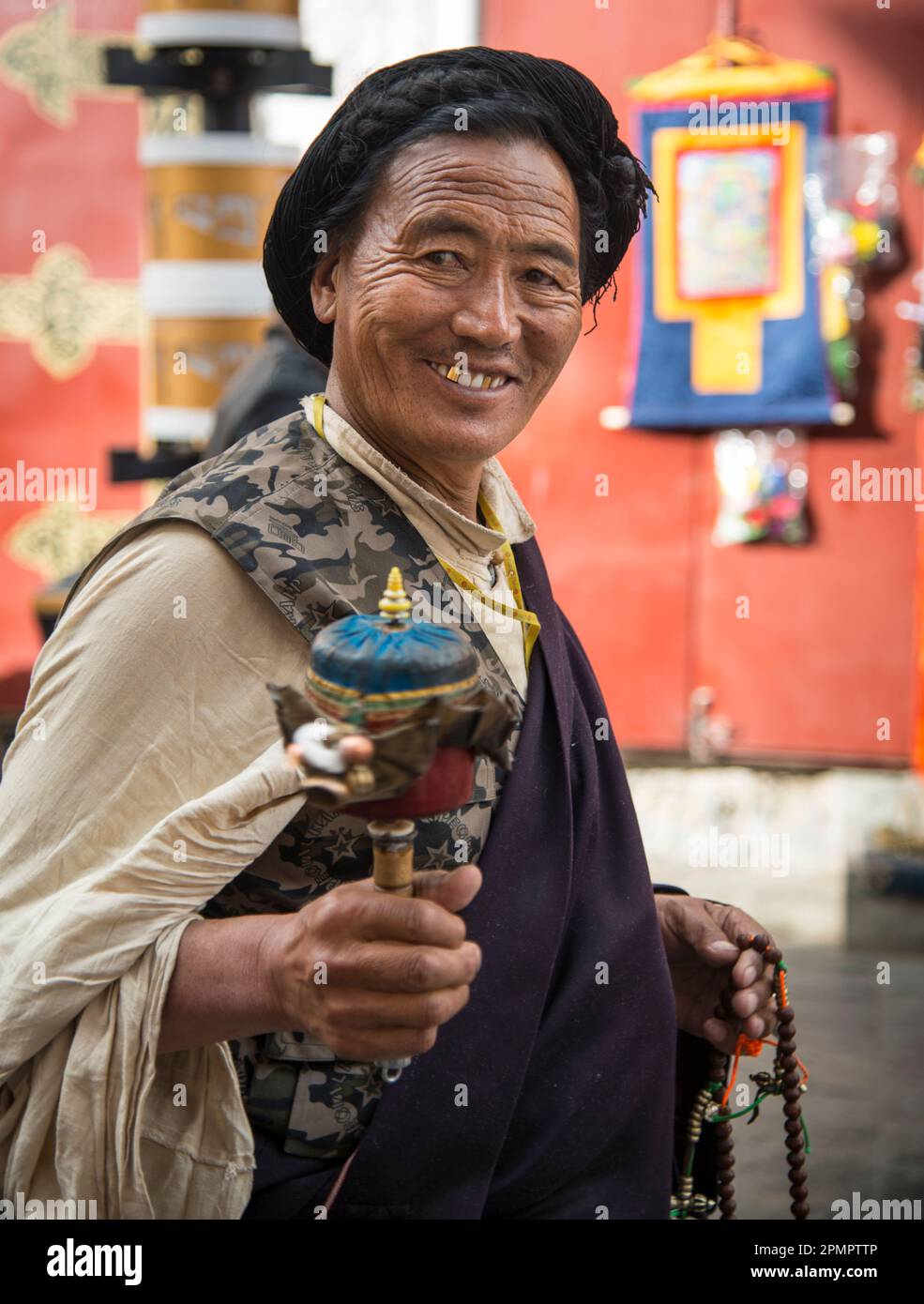 Tibetan man in traditional clothing holding a prayer wheel; Lhasa ...