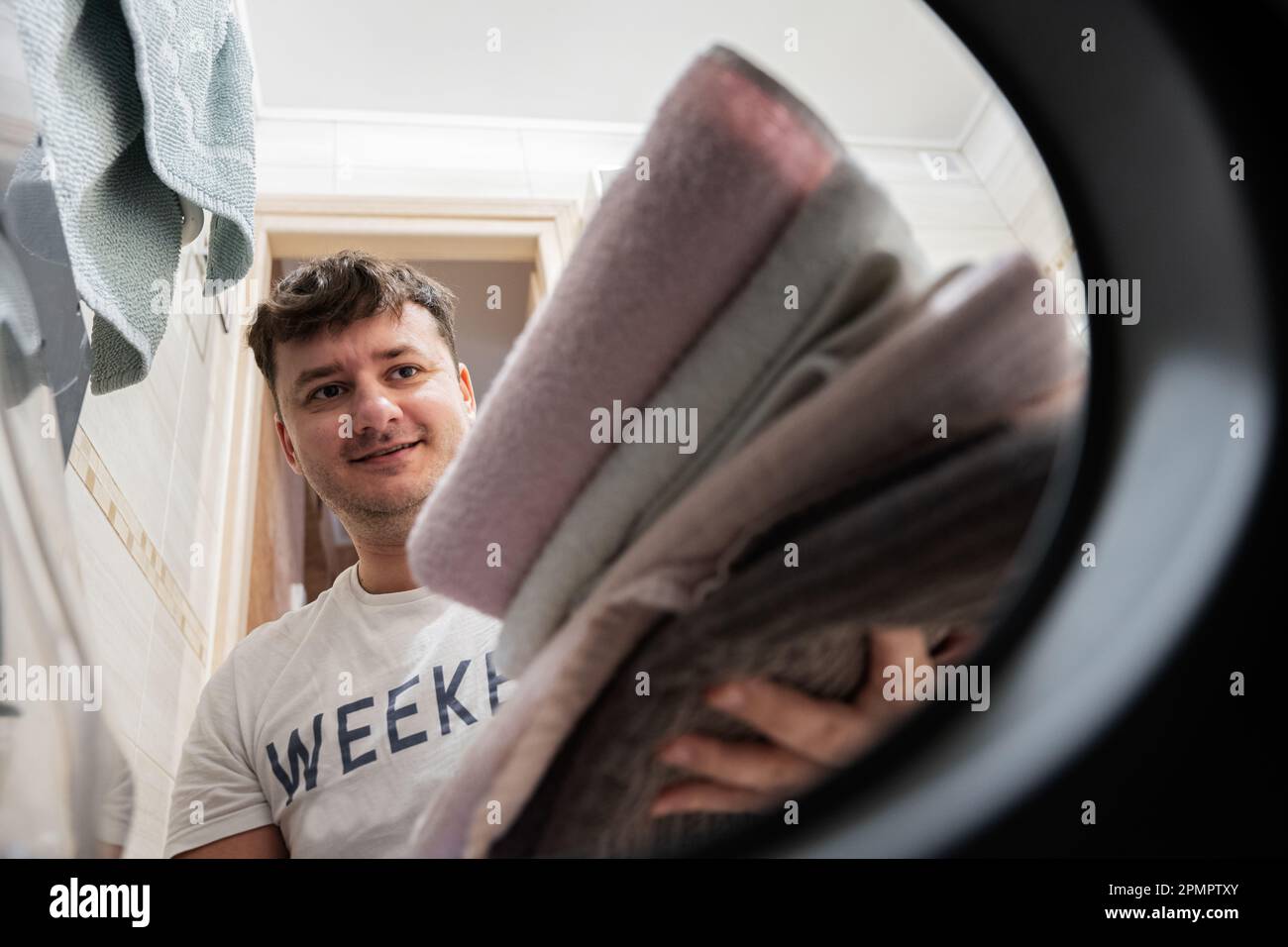 Man view from washing machine inside. Male does laundry daily routine ...