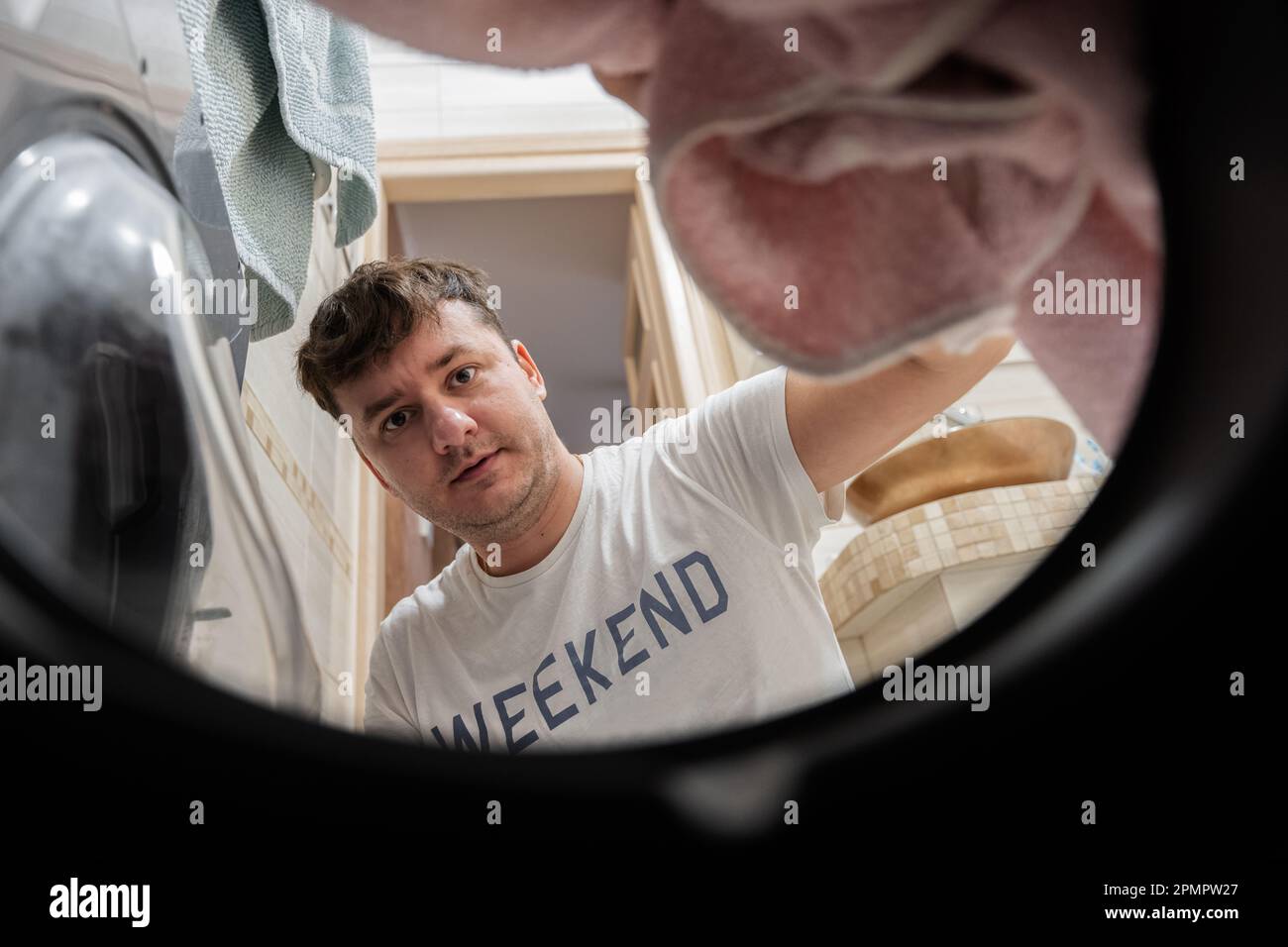 Man view from washing machine inside. Male does laundry daily routine ...