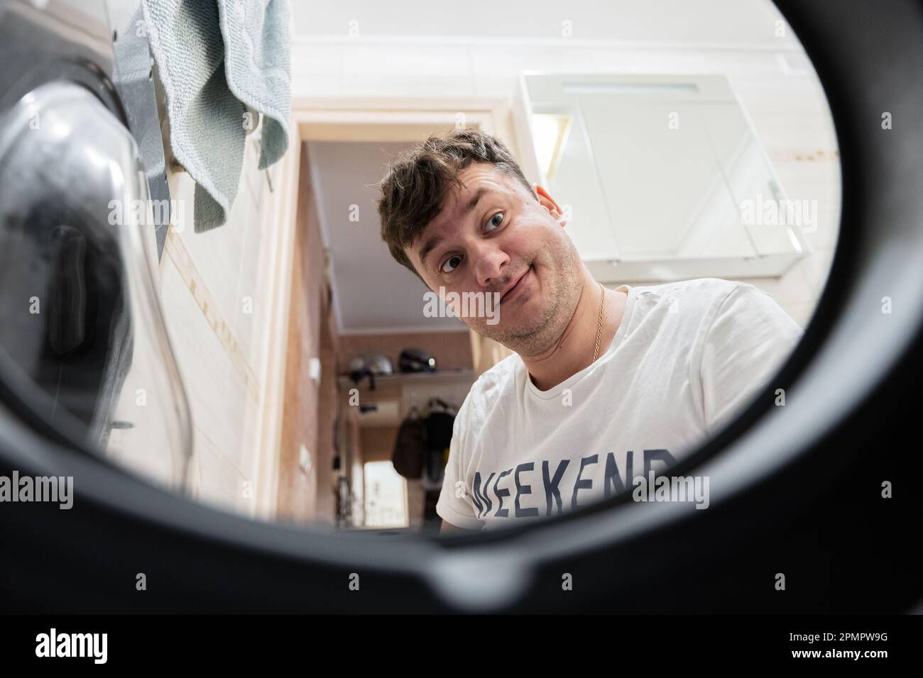 Man view from washing machine inside. Male does laundry daily routine ...
