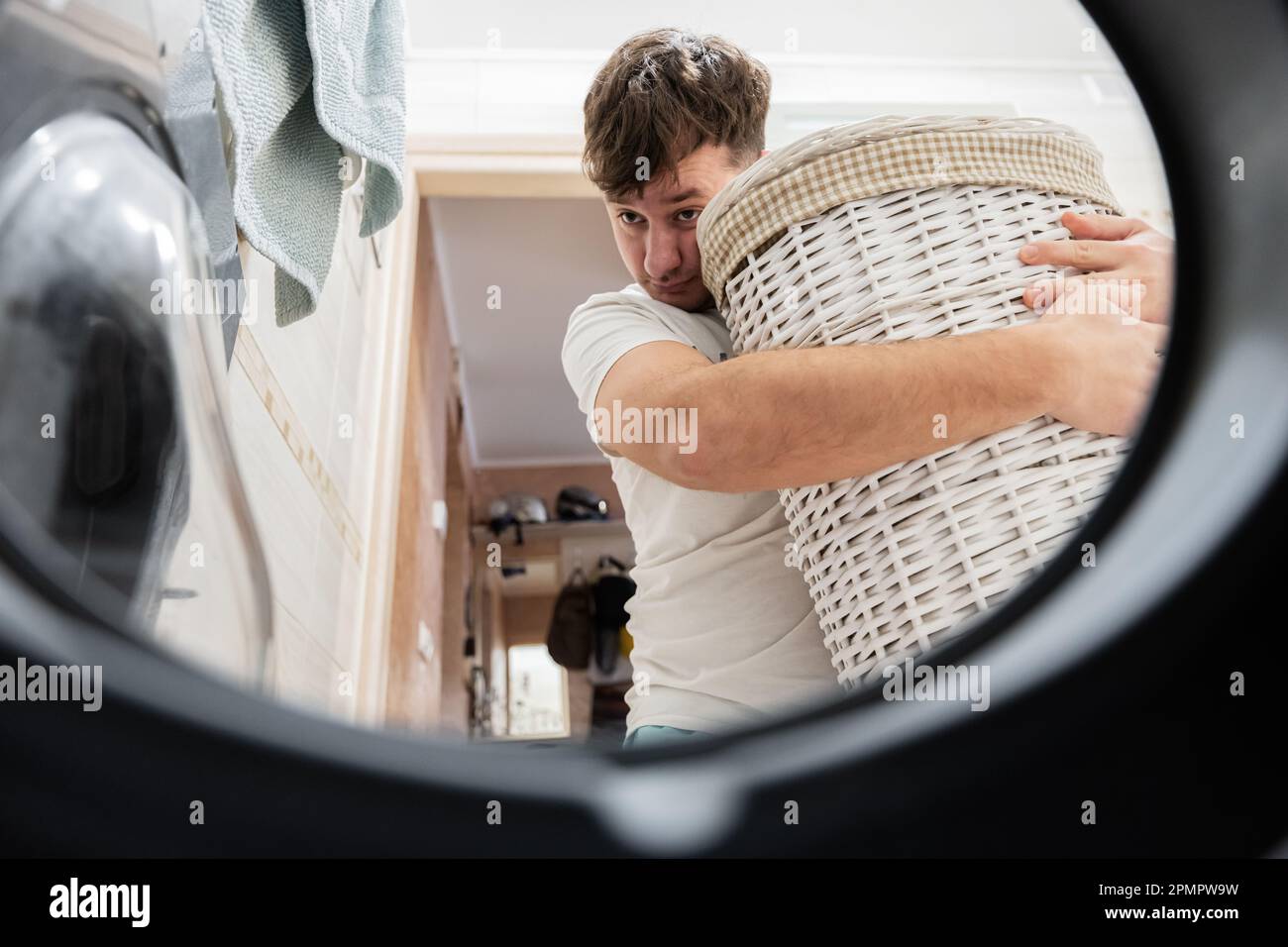 Man with basket, view from washing machine inside. Male does laundry ...