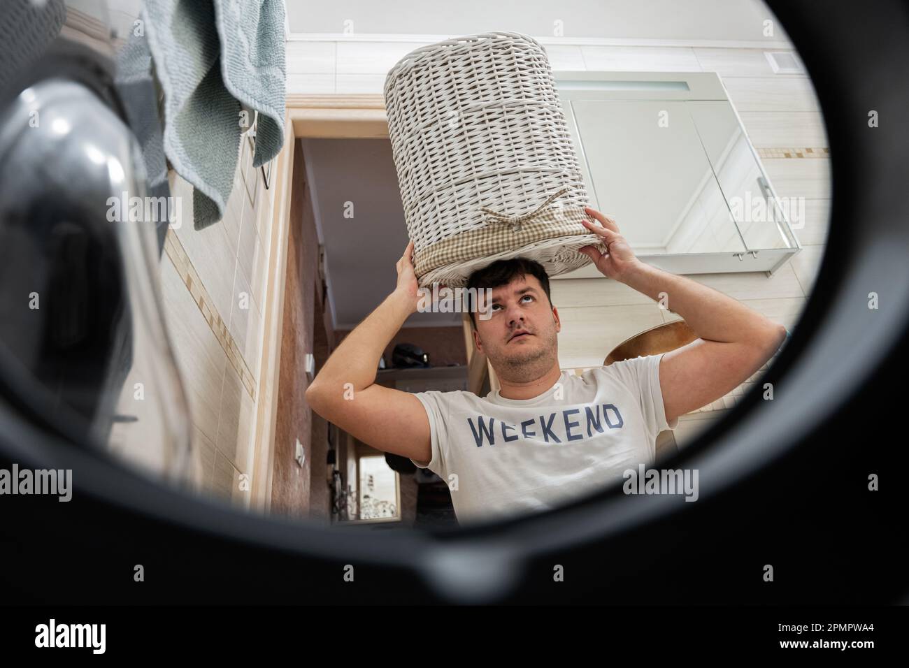 Man with basket on head, view from washing machine inside. Male does ...
