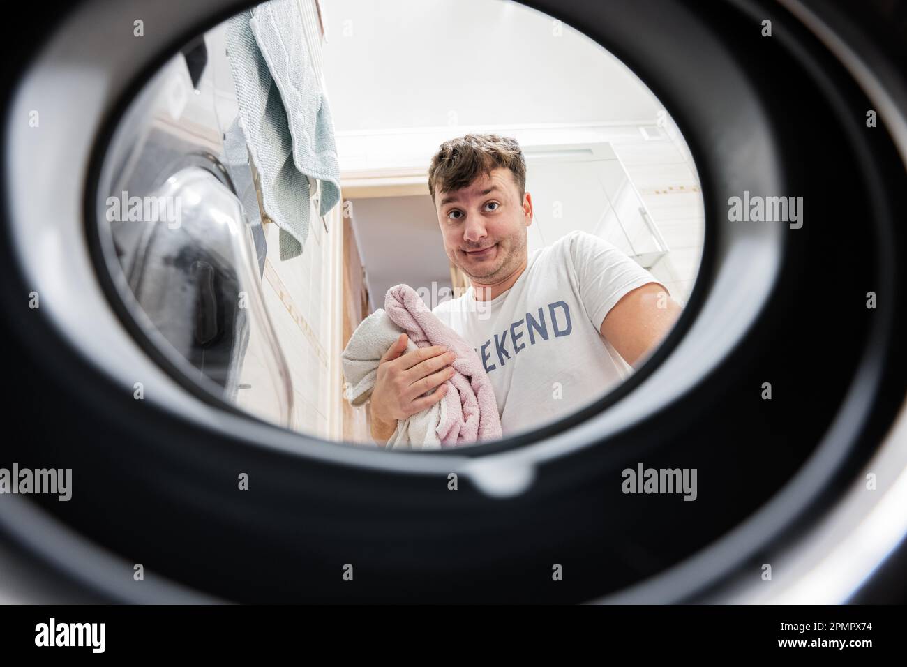 Man view from washing machine inside. Male does laundry daily routine ...