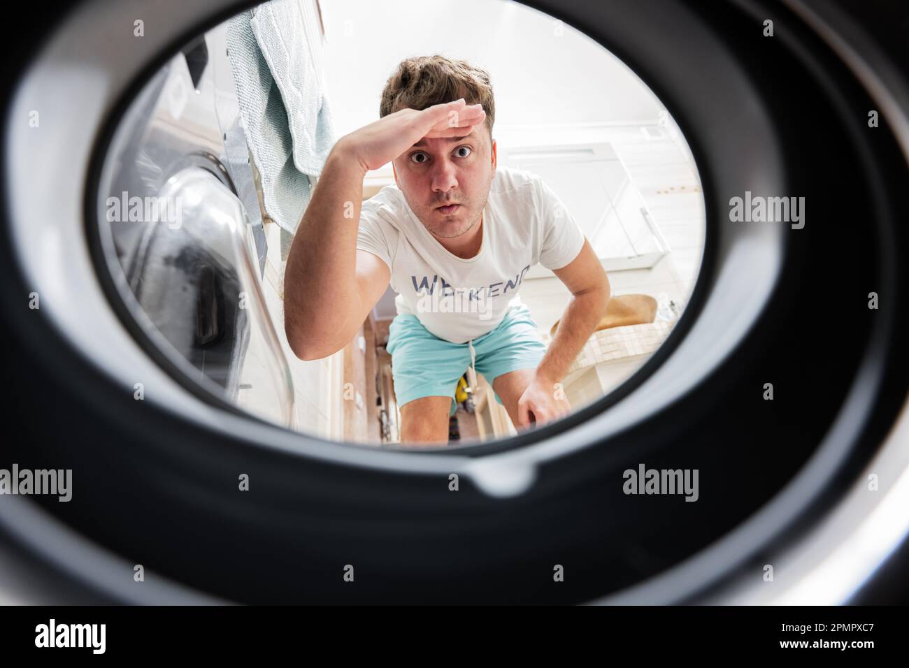 Man view from washing machine inside. Male does laundry daily routine ...