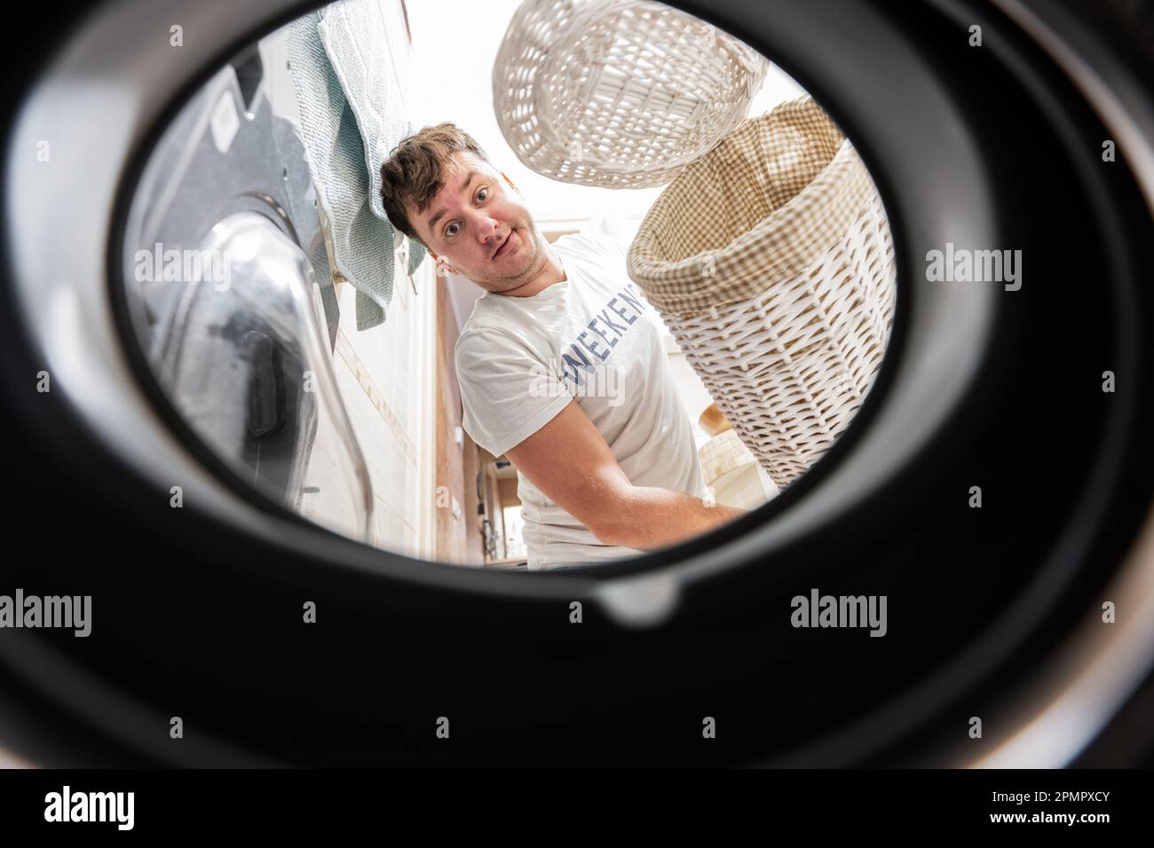 Man with basket, view from washing machine inside. Male does laundry ...