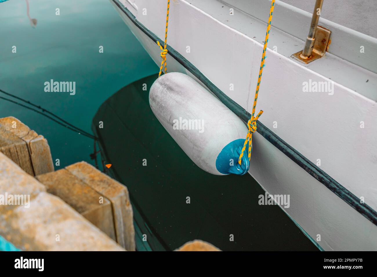 White fenders suspended between a boat and dockside for protection ...