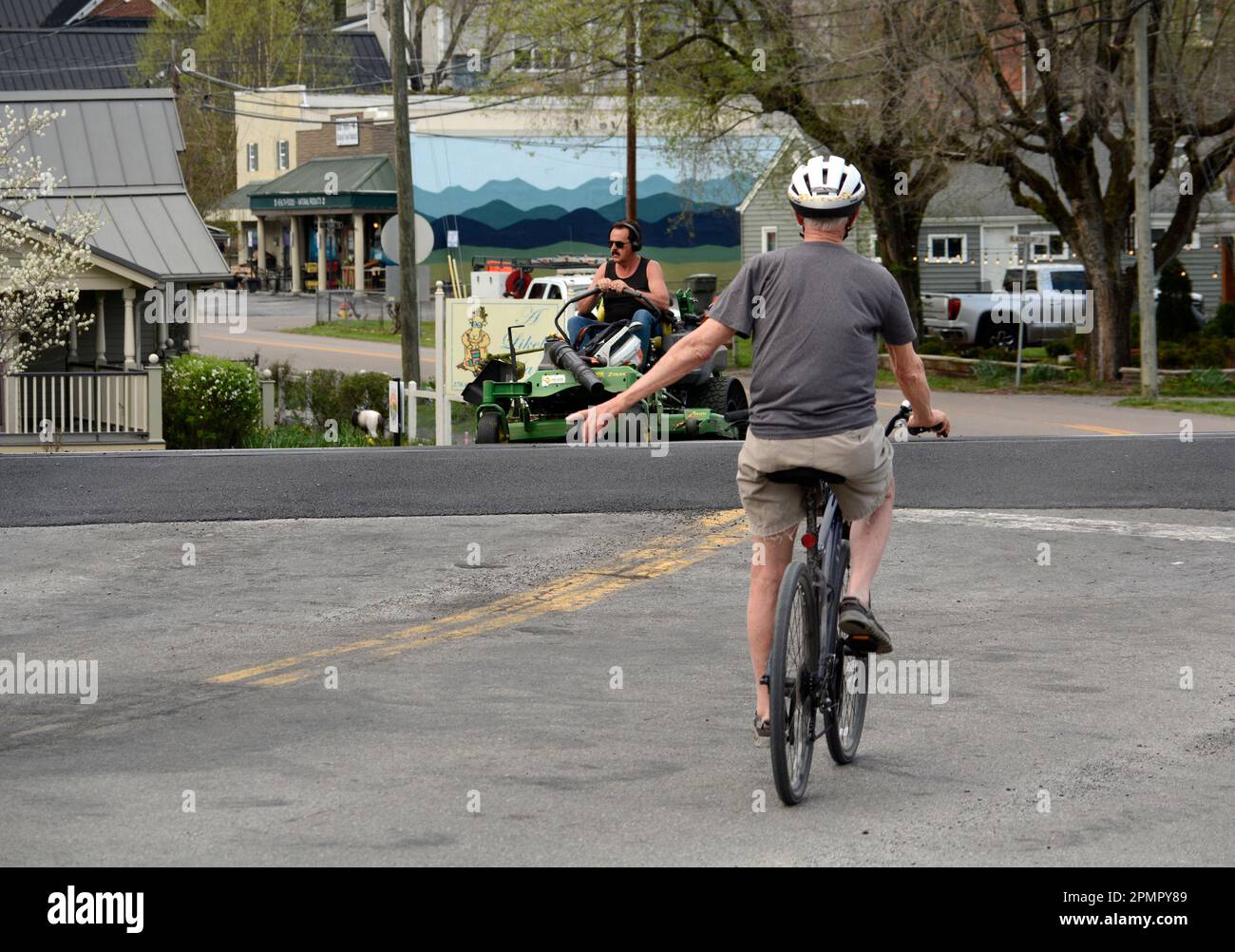 A senior man riding a bicycle signals a left turn as he rides along a ...