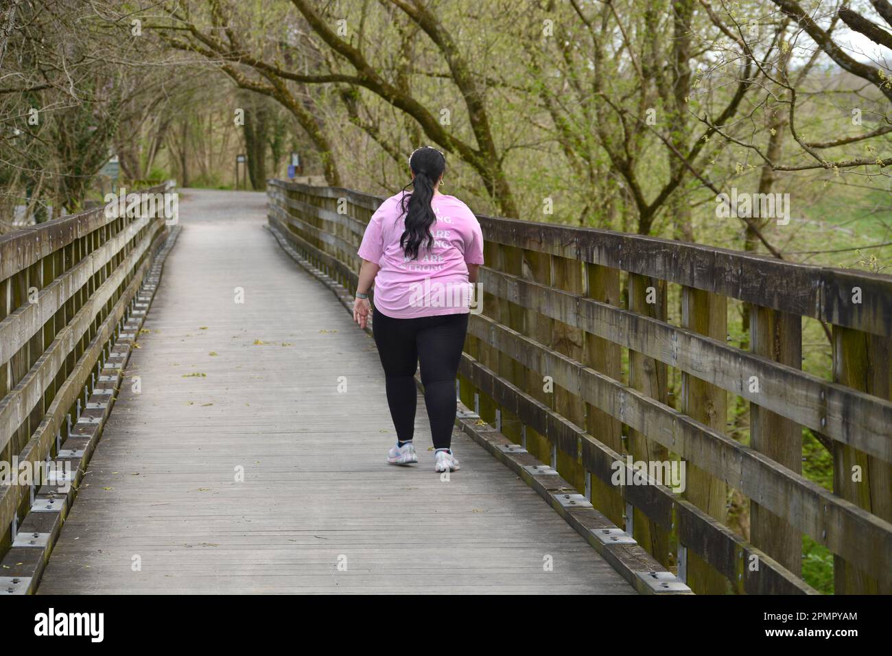 A woman enjoys a spring walk along a walking and biking trail in ...