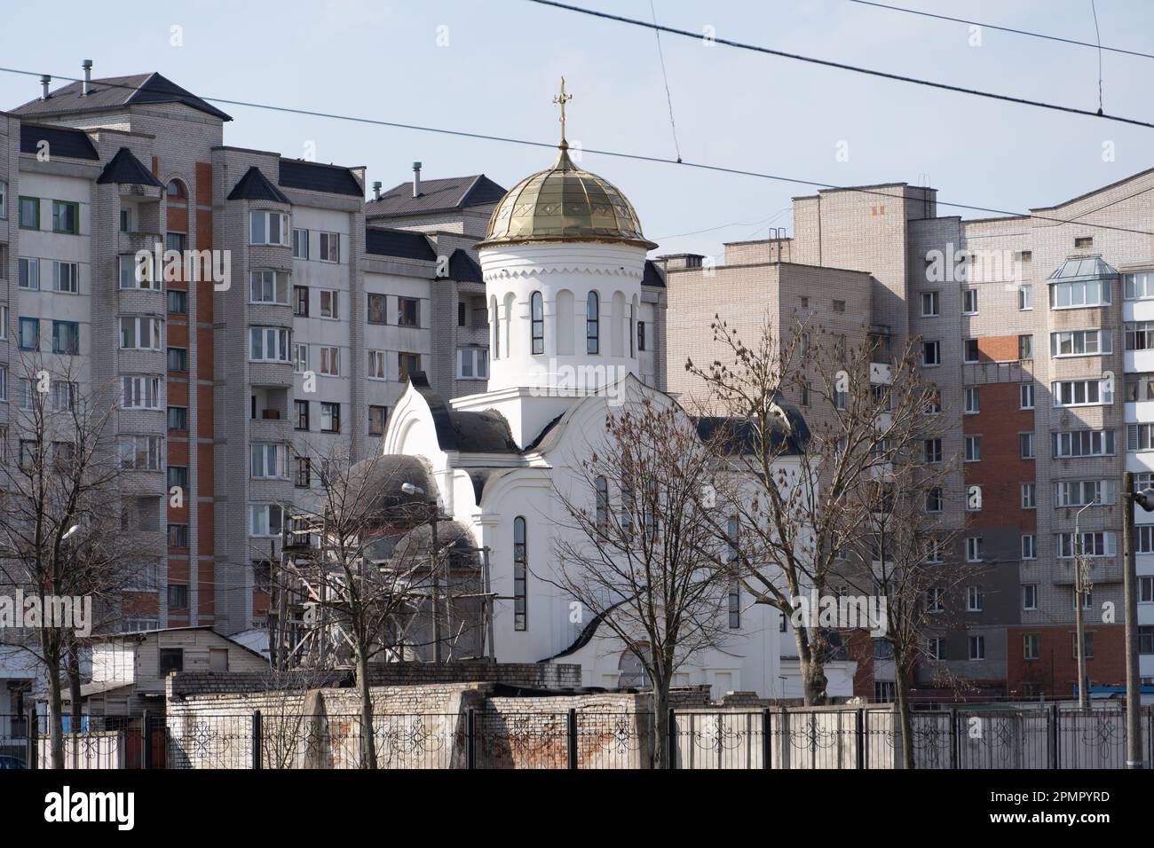 Orthodox white church with golden domes among multi-storey buildings ...