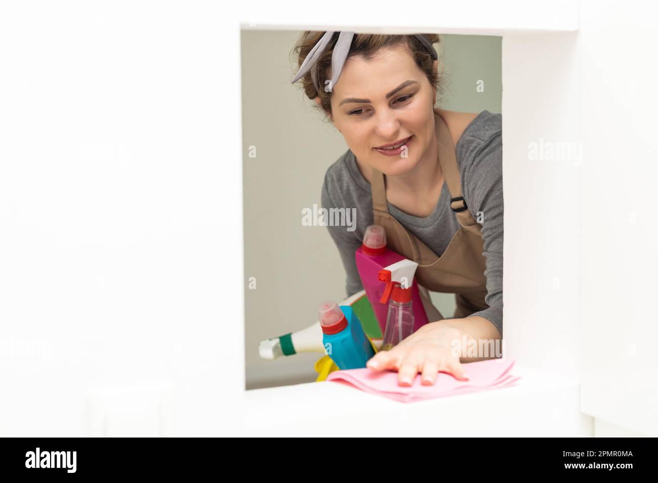 Woman cleaning and polishing the kitchen worktop with a spray detergent ...