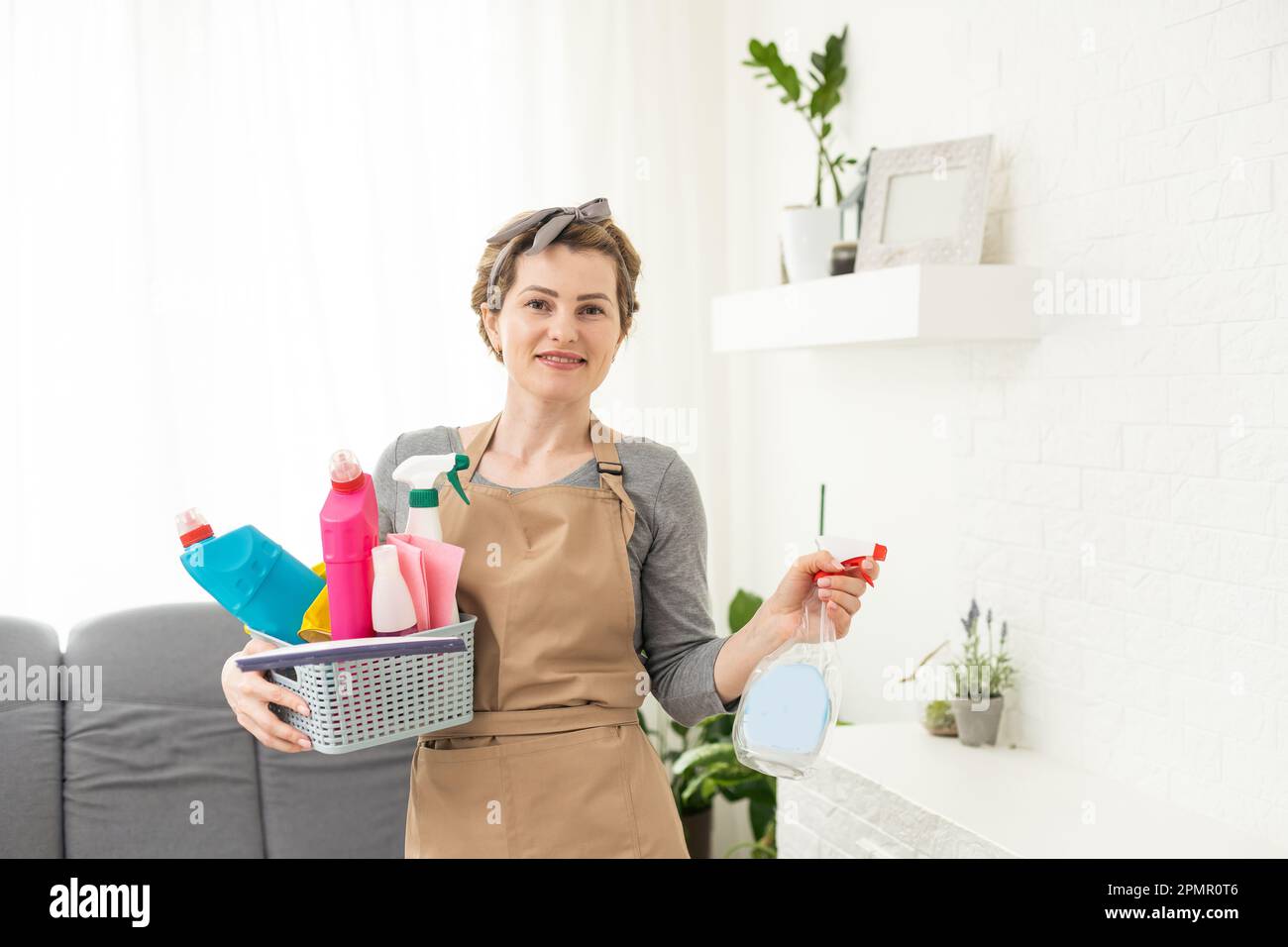 Woman cleaning and polishing the kitchen worktop with a spray detergent ...
