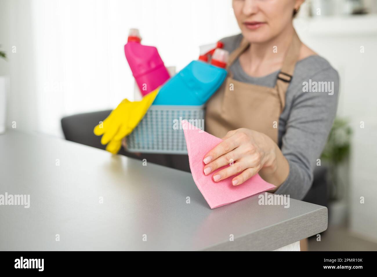 Woman cleaning and polishing the kitchen worktop with a spray detergent ...